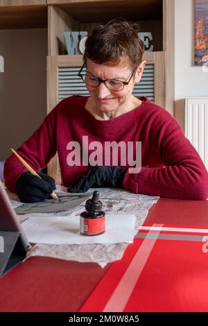 Woman draws in ink with a feather Stock Photo - Alamy