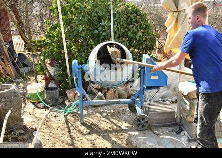 The mason loads the sand manually with a shovel into the concrete ...