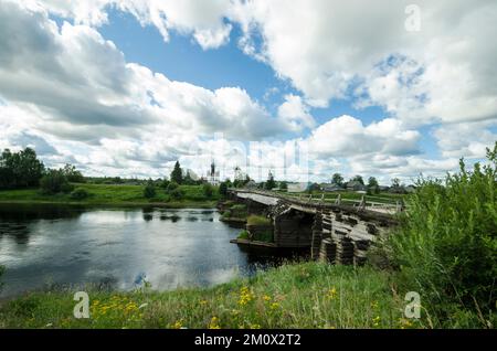Dilapidated crooked emergency bridge across the river. Road to the ...