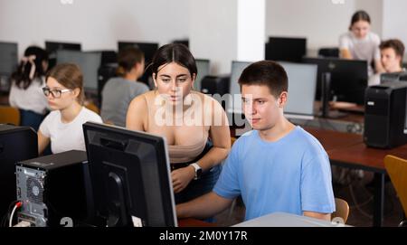 Smart female teenager giving a clue to the female co-learner while she ...