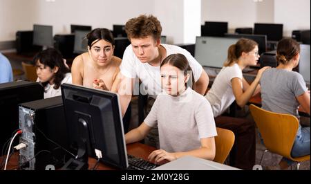 Clever male teenager helping to the female classmate while she is ...