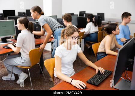 Portrait of interested teen girl during lesson in computer room of ...
