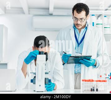 scientists with clipboard and microscope in lab Stock Photo - Alamy
