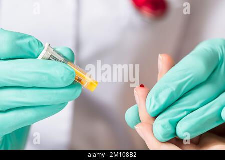 Doctor piercing patients finger with lancet in clinic closeup. Taking ...