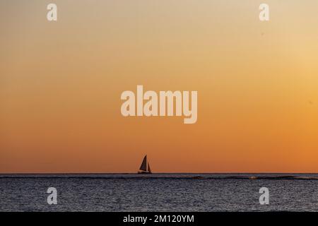 A lonely saling ship at the horizon during sunset at Mauritius Island ...