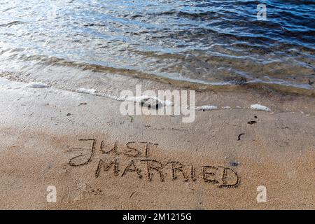 JUST MARRIED message written with a finger in the sand on a beach with ...