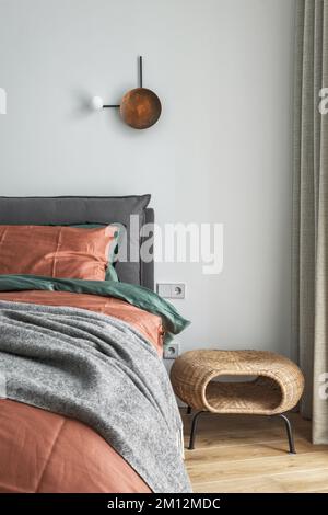 Bedroom interior with rust color linen and cushions on a bed, grey ...