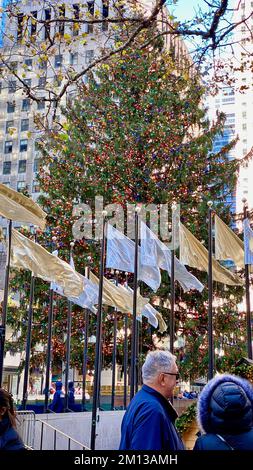 A large Christmas tree stands with ornaments and lights beside a white ...