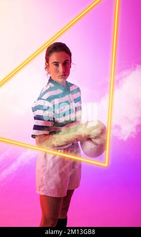 Caucasian female rugby player holding ball and standing over ...