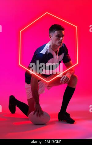 Confident male caucasian rugby player with hands on hip by illuminated ...