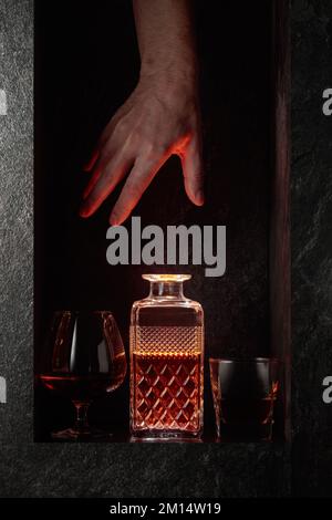Hand reach for a decanter of strong alcoholic drink. A concept image on ...