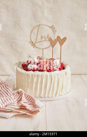 A vertical closeup of a wedding cake with fruits and topping on a white ...