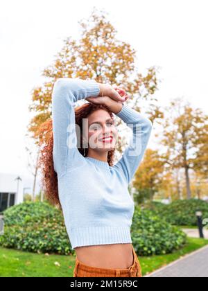 Delighted young female millennial with long curly ginger hair and red ...