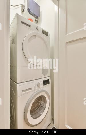 Modern washing and dryer machines placed in light bathroom with white ...