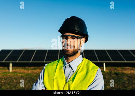 Serene bearded installer in helmet with crossed arms closing eyes near ...
