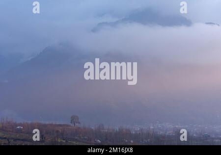 Sunrays pass through clouds covered mountain during a cold evening ...