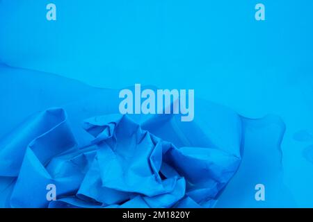 Crumpled paper put in water in blue background Stock Photo - Alamy