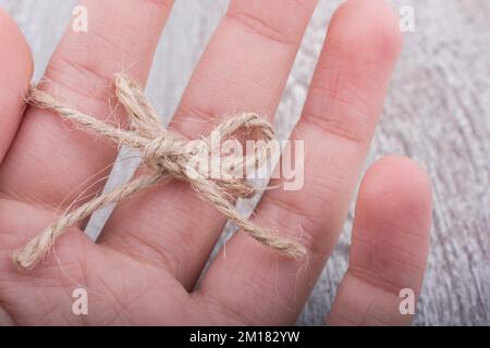 Thread knot in hand on a light color background Stock Photo - Alamy