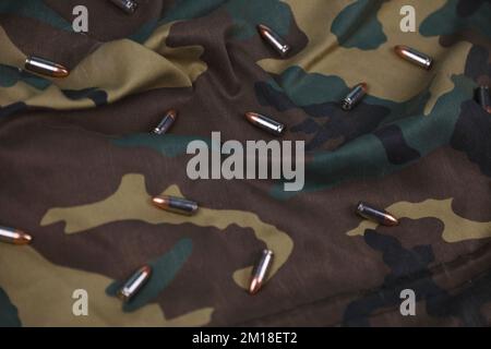 Many pistol bullets and cartridges on dark camouflage background ...