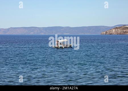 Lesbos scenes. Small Greek fishing boat with family aboard, low in the ...