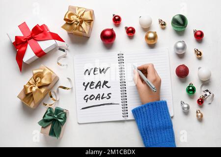 Woman making to-do list for year 2023 on light blue background, top ...