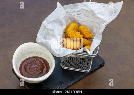 A closeup of fried chicken nuggets served with ketchup and beer in a ...