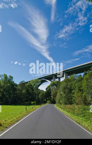 Freeway viaduct spanning across a green valley with a paved road Stock ...