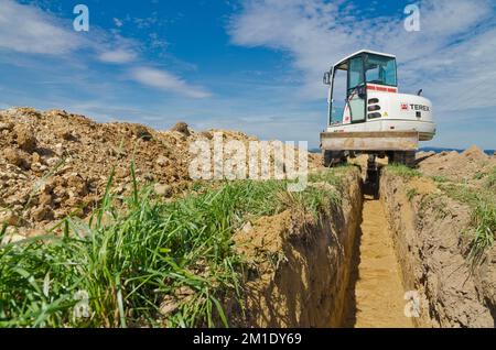 Excavator digging a channel through agriculture landscape Stock Photo ...