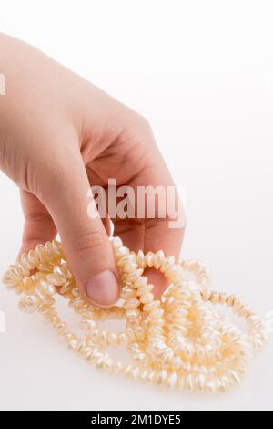 Hand holding pearl necklace on white background Stock Photo - Alamy