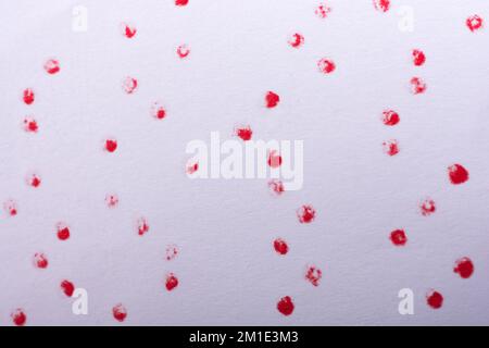 Red paint dots on a white background on display Stock Photo - Alamy