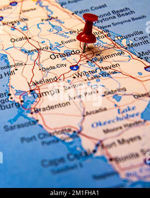 A vertical closeup shot of a traveling red push pin on a map on the ...