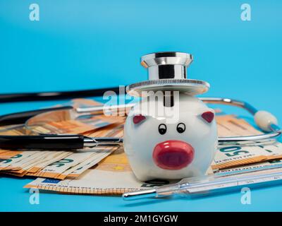 Medical stethoscope, piggy bank, thermometer and banknotes on a blue ...