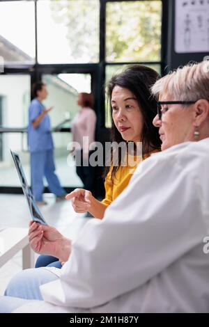 Senior physician explaining bones radiography diagnosis to asian woman ...