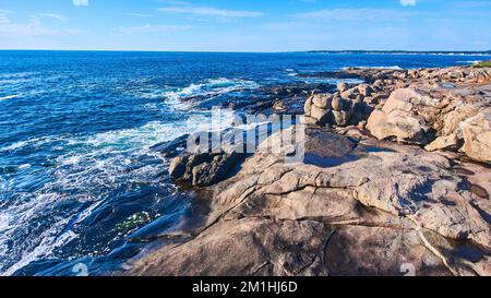 Rocky coasts of Maine on ocean during low tide with small green algae ...