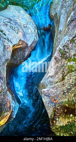 Between rocks falls a raging mountain stream of clear water ...