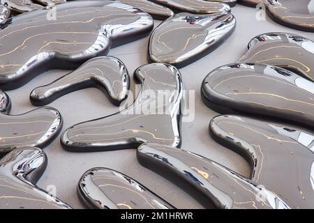 Ground detail of art exhibit melting reflecting shiny metal mirror ...