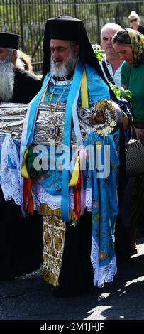 A Greek Orthodox priest carrying a silver icon of the Virgin Mary ...