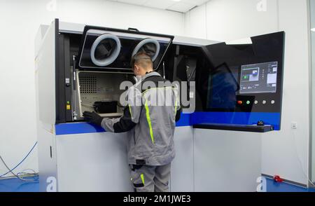 The worker controls workflow inside large industrial 3D printer ...