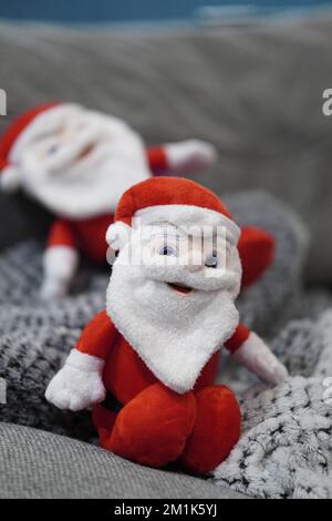 Santa Claus plush toy sitting amidst a festive Christmas scene. The ...