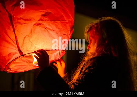 lovely girl with orange fortune paper balloon in hands prepared to fly ...