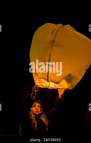 lovely girl with orange fortune paper balloon in hands prepared to fly ...