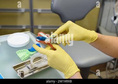 The orthodontist prepares a special paste for making an impression of ...