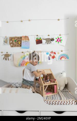 Non binary diverse male kid playing wooden dolls house enjoy happy ...