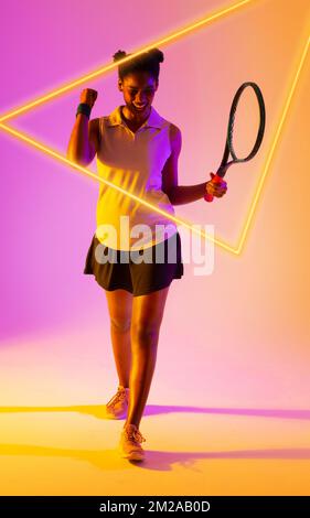 Happy african american tennis player holding racket by illuminated ...