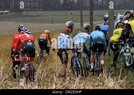 Riders pass through a field after a fall during the 61st edition of the ...