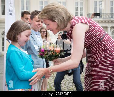 Queen Mathilde of Belgium (L) receives flowers from a child at the ...