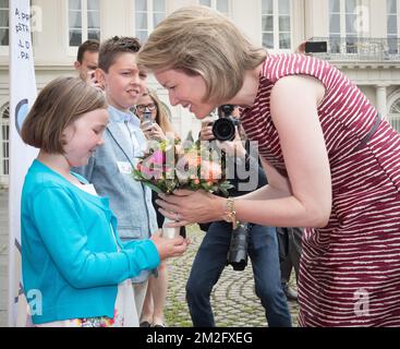 Queen Mathilde of Belgium (L) receives flowers from a child at the ...