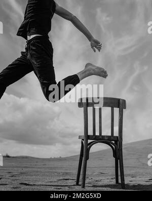 Man jumping over chair in desert Stock Photo - Alamy