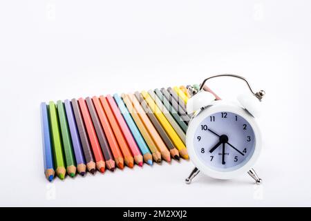Colour pencil with alarm clock on a white background Stock Photo - Alamy