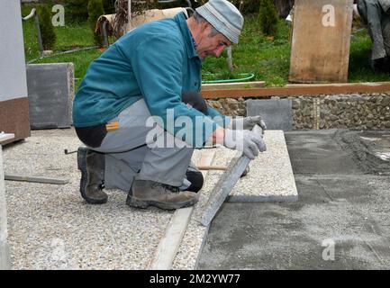 The bricklayer levels the floor using a spirit level and sand before ...
